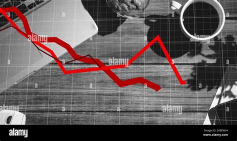 Red Line Graph Displaying Decline Covering A Desk With A Laptop And