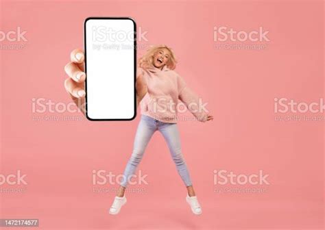 모바일 앱 이나 웹 사이트 Desing 모형을위한 빈 공간과 함께 점프하고 휴대 전화를 보여주는 쾌활한 여자의 전체 길이 금발 머리에 대한 스톡 사진 및 기타 이미지