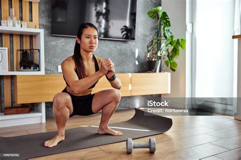 A Pretty Barefoot Asian Woman Doing A Squats Workout In A Sportswear At