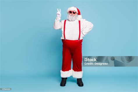 재미 큰 복부 배와 힙스터 안경에 뚱뚱한 펑키 재미 산타의 전체 크기 사진은 V기호가 크리스마스 노엘 시간을 즐길 수 있도록 바지 바지 빨간 서스펜더 는 파란색 배경 위에