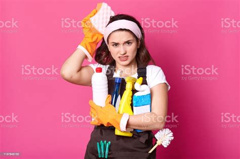 아름 다운 얼굴 표현으로 백인 젊은 여자의 실내 촬영 청소 세제를 보유 머리에 손에 스폰지와 손을 유지 분홍색 스튜디오 배경 위에 고립 집안일을 할 준비가 가사 집안일에