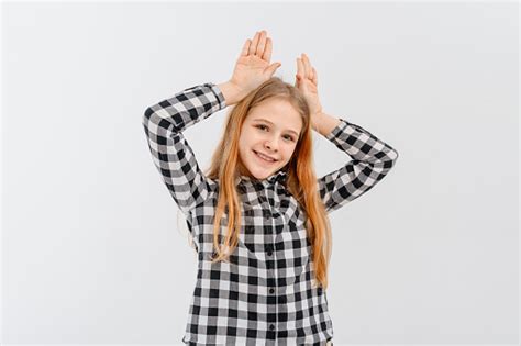 흰색 배경 위에 서서 토끼 귀 제스처를 하는 재미있는 십 대 소녀는 손바닥이 행복하고 기뻐 보인다 부활절 토끼 개념입니다 행복한 부활절을 기원하는 귀여운 젊은 여자 십대에