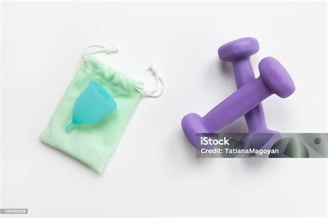 녹색 작은 가방에 청록색 생리 컵과 흰색 배경에 보라색 아령 개념 제로 폐기물 저축 미니멀리즘 제한없음 피트니스 플랫 레이를 위한 여성 위생 제품 수평 운동에 대한 스톡