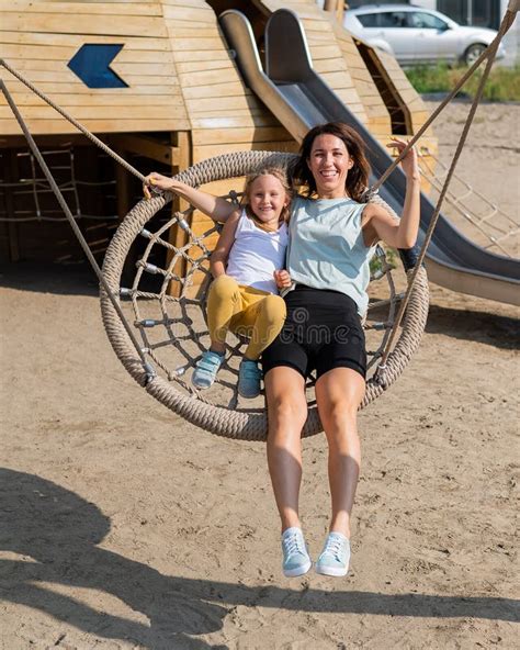 Mom And Daughter Swing On A Round Swing Caucasian Woman And Little