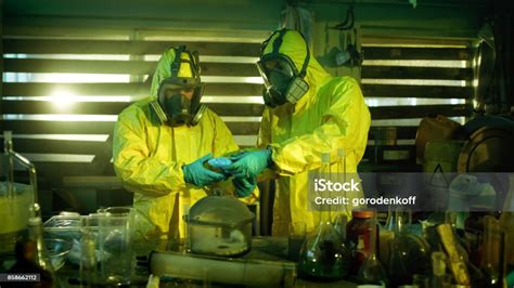 지 하 실험실에서 2 명의 은밀한 화학자 상자에 약물의 가방을 팩 실험실 유리 그릇 전체 및 기타 마약 생산 관련 장비입니다 그들은 버려진된 건물에 쪼 그리고 앉아서