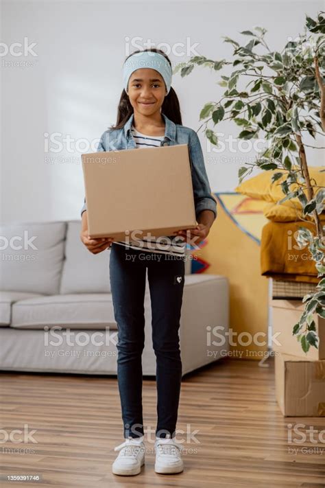 달콤한 소녀는 이동하는 동안 그녀의 부모를 돕고 골판지 상자에 포장 된 방에서 물건을 운반하고 상자를 운반하고 이사하고 아파트 집을 임대합니다 구매에 대한 스톡 사진 및