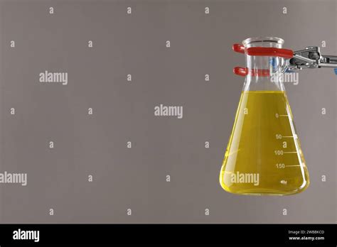 Retort Stand And Laboratory Flask With Liquid On Light Grey Background Closeup Space For Text