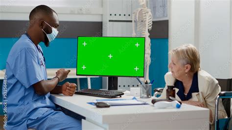 Specialist And Old Woman Using Greenscreen Monitor In Cabinet Patient With Physical Disability