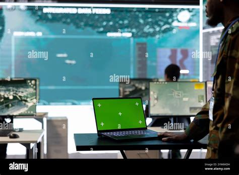 Army Trooper Examines Green Screen Layout On A Laptop In Control Center