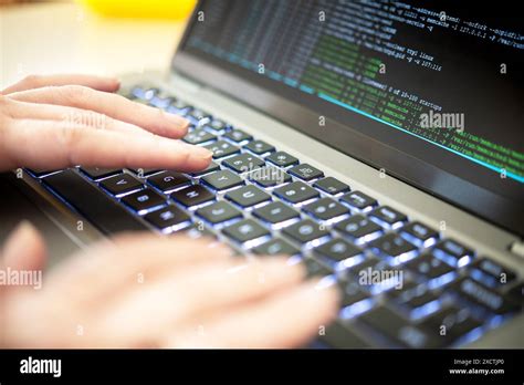 A Persons Hands Are Typing On A Laptop Displaying Hacker Code Highlighting Issues Of Cyber