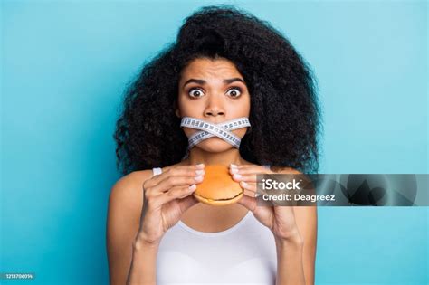 손 버거 제한 입에 들고 좋은 매력적인 무서운 물결 모양의 소녀의 클로즈업 초상화 밝은 선명한 빛선명한 푸른 색 배경에 고립