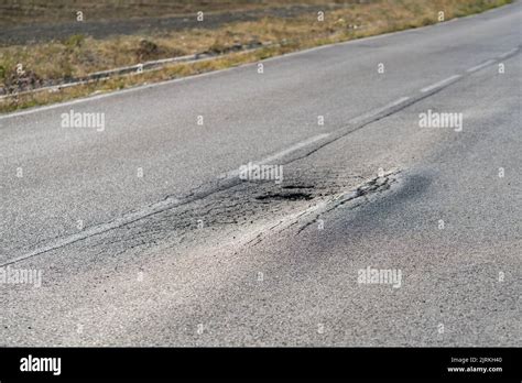 Deformed Asphalt Surface With Potholes Caused By Heavy Overloaded Trucks Driving On Highway