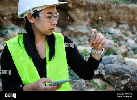 Female Geologist Using Mobile Phone To Record Data Analyzing Rocks Or Gravel Researchers