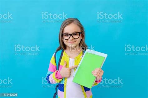 그녀의 손에 서류 가방과 책과 파란색 고립 된 배경에 안경을 가진 귀여운 소녀 여학생은 수업과 미소 텍스트 공간을 보여줍니다 6
