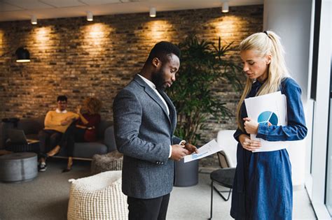사무실 로비에서 그래프와 차트를 보고 있는 두 명의 비즈니스 동료의 공간 사진 복사 20 24세에 대한 스톡 사진 및 기타 이미지 20 24세 25 29세 30 34