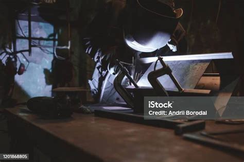 용접기 마스크의 작업자는 철 용접 작업장에서 일합니다 남자는 철 제품을 만든다 남자는 위험한 광선으로부터 자신의 눈을 보호하기 위해 마스크를 사용하여 용접 기계와 함께 작동