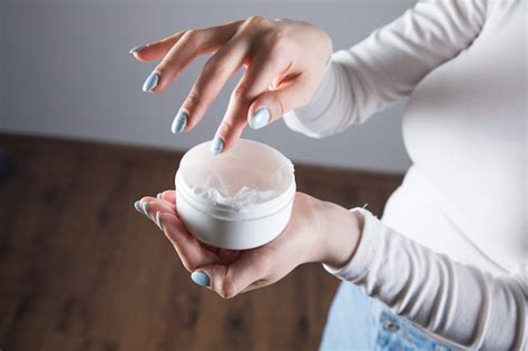 Premium Photo Young Girl Rubs Her Hands With Cream On A Gray Scene