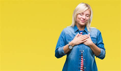 함께 웃 고 고립 된 배경 위에 데님 자 켓을 입고 젊은 아름 다운 금발의 여 자가 가슴 닫힌된 눈과 얼굴에 감사 제스처에 손 건강 개념입니다 감사에 대한 스톡 사진 및