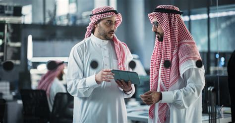 두 명의 다민족 아랍 동료가 소프트웨어 개발 프로젝트를 진행하는 동안 대화를 나누고 있습니다 사무실에서 태블릿 컴퓨터를 사용하여 중동 프로젝트 관리자와 대화하는 엔지니어