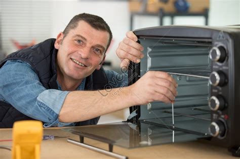 작은 오븐을 수리하는 기술자 사진 사진 무료 다운로드 Lovepik