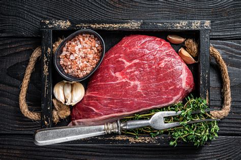 허브가 있는 나무 트레이에 고기 스테이크나 피칸하를 잘라낸 생 탑 등심 캡 쇠고기 검은 색 나무 배경 위쪽 보기 피카냐에 대한 스톡 사진 및 기타 이미지 Istock