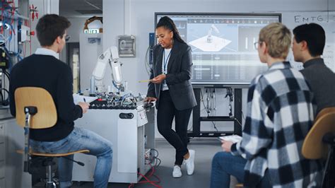 대학 로봇 수업 로봇 팔을 사용하는 학생들에게 공학을 설명하는 흑인 교사 로봇 손을 프로그래밍하는 젊은 엔지니어의 다양한 그룹 컴퓨터 과학 교육 빌드 디자인 배우기 교실에