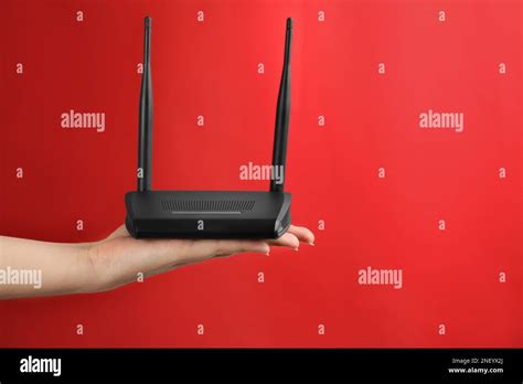 Woman Holding Modern Wi Fi Router On Red Background Closeup Space For