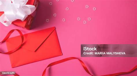 กล่องของขวัญแบนพร้อมโบว์ริบบิ้นสีขาวซองสีแดงบนพื้นหลังสีชมพู การเฉลิมฉลองวันวาเลนไทน์แ ภาพสต็อก