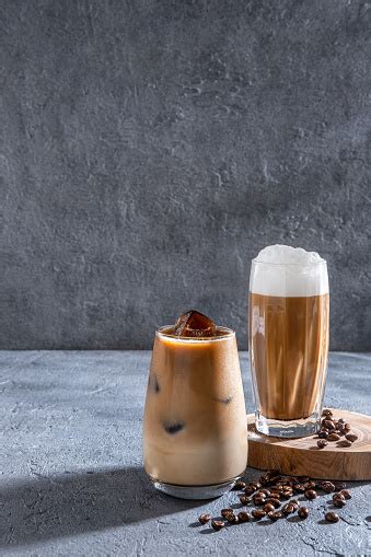 크림을 붓고 커피 원두를 얹은 키 큰 유리에 아이스 커피 복사 공간이있는 어두운 배경에서 차가운 커피를 마 십니다 어두운 테이블에 다양한 종류의 커피 음료가 놓여 있습니다