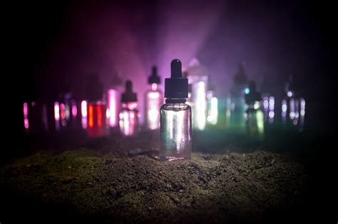 Vape 개념입니다 구름과 어두운 배경에 Vape 액체 병 연기 빛 효과입니다 배경 또는 Vape 광고 Vape 배경으로 유용 합니다 개념과 주제에 대한 스톡 사진 및 기타