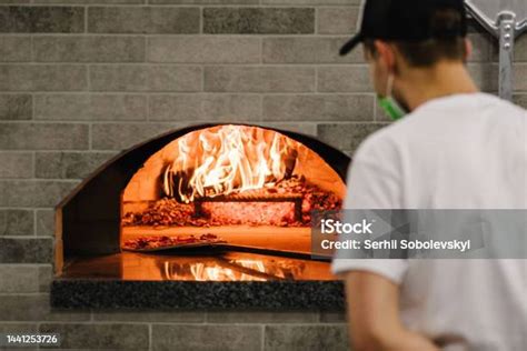 요리사는 Margherita 4 개의 치즈 또는 고기 피자를 오븐의 삽에 넣습니다 피자를 요리하고 굽기 위한 장작 오븐 이탈리아 전통 피자는 돌로 만든 장작 오븐에서