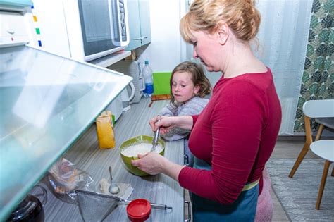 7 세의 백인 소녀 인 여성과 어린이가 부엌에서 피자 반죽을 준비하고 있습니다 아이는 집안일로 어머니를 돕고 가사일을 배우고