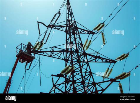 High Voltage Power Line Transmission Tower Workers With Crane And Blue Sky Hydro Linemen On
