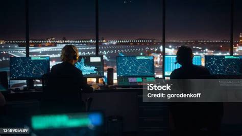 밤에 현대 공항 타워에서 일하는 다양한 항공 교통 관제 팀 사무실 방은 네비게이션 화면 컨트롤러에 대한 비행기 비행 레이더 데이터와 데스크톱 컴퓨터 디스플레이의 전체입니다