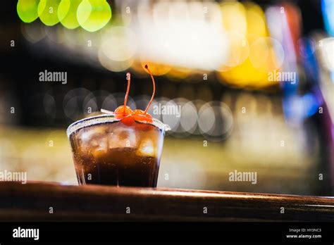 Short Cocktail Glass With Alcohol Ice Cubes And Glacé Cherry Stock
