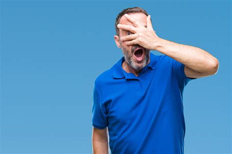 중 년 노인의 수석 남자 충격 얼굴과 손으로 눈을 덮고 엿보기 격리 된 배경 위에 당황된 하는 표정으로 손가락을 통해 찾고