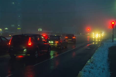 안개가 낀 날씨 밤 안개 도로에서 시야가 좋지 않습니다 자동차의 움직임 교통 체증 젖은 미끄러운 아스팔트 자동차 헤드 라이트 빛의 광선 도로에 눈과 얼음 도시 거리 도시에