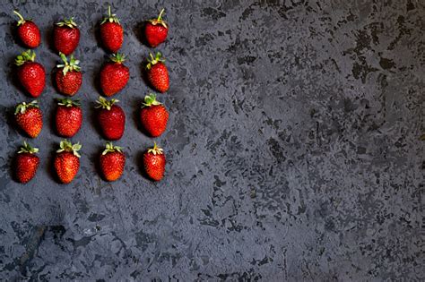 어두운 배경의 왼쪽 상단 모서리에있는 사각형 모양의 잘 익은 빨간 딸기 그룹 딸기 패턴 어두운 낮은 키 사진 공간을 복사합니다