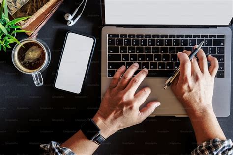 탑 뷰 남자는 어두운 책상과 용품에 격리된 화면이 있는 노트북 키보드에 타이핑을 합니다 사진 Unsplash의 랩톱 이미지