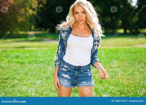 Beautiful Blonde Woman Dressed In A Denim Jacket And Shorts Stock Image