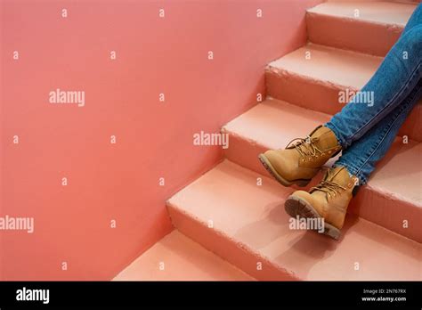 Legs In Blue Jeans Brown Boots On Pink Staircase Copy Space For Advertising Relax Color