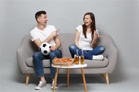 명랑 한 커플 여자 남자 축구 팬 응원 축구 공 좋아하는 팀 회색 벽 배경에 고립 된 인덱스 손가락 포인팅 사람들의 감정 스포츠 가족 레저 라이프 스타일 개념입니다 2020