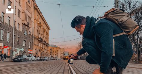 검은색 재킷과 파란색 데님 청바지를 입은 남자가 스마트폰을 들고 낮에 보도에 앉아 있다 사진 Unsplash의 무료 사람의 이미지