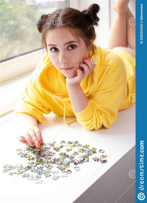 Pretty Brunette Girl In Yellow Hoodie Arranging Pieces Of A Jigsaw