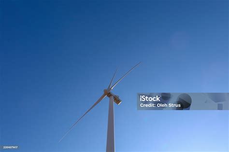밝고 푸른 하늘을 배경으로 한 풍력 터빈 블레이드와 나셀을 포함한 전체 풍력 터빈이 보입니다 사진은 현대 재생 가능 에너지 기술과 그 환경 친화성을 전달하고 0명에 대한