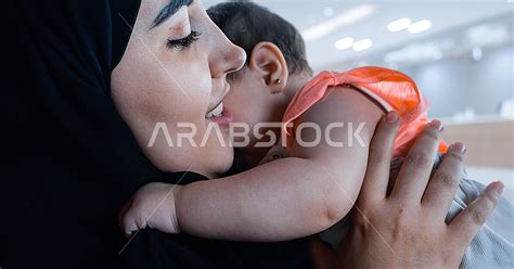 صورة مقربة لأم عربية خليجية سعودية تحتضن طفلتها الرضيعة بسعادة وحنان
