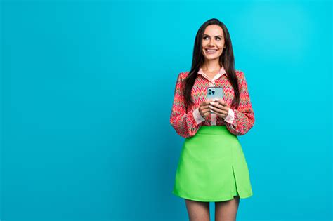 매력적인 젊은 여자의 사진 초상화 가제트 보기 관심 있는 빈 공간 착용 청록색 배경에 고립된 유행 녹색 치마 Brand Name Smart Phone에 대한 스톡 사진 및