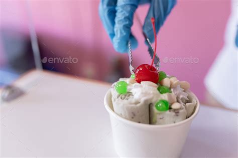 Close Up Of A Worker Is Decorating A Rolled Ice Cream Tub With A Cherry