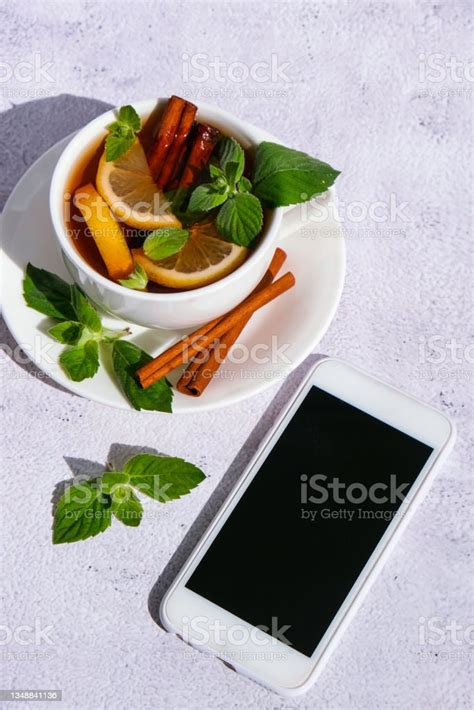 레몬 계피 스틱 민트 잎이 있는 블랙과 녹차와 휴대폰이 있는 테이블에 놓입니다 소셜 미디어 건강한 멜리사 차 천연 유기농 아로마 드링크 여름 가을 겨울 따뜻한 음료 탁자에