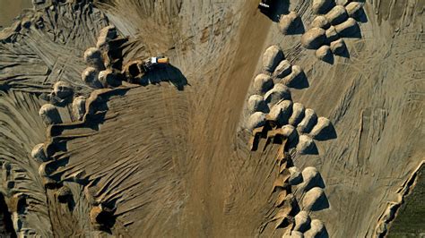 노천 모래 광산의 아리알 전망 프론트 로더는 더미에서 모래를 적재합니다 채석장에서 일하는 무거운 광산 기계 많은 바퀴 트랙과 사막 모래 언덕이나 가슴과 같은 모래 더미 건조